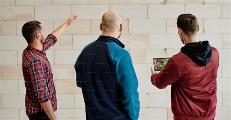 스타트업 회의에서 미완성 건물의 벽을 구성하는 벽돌의 품질에 대해 논의하는 세 명의 젊은 건축업자 또는 건축가의 뒷모습 사진 Unsplash의 성공 이미지