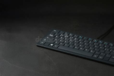 A Black Coloured Computer Keyboard On A Black And Textured Background