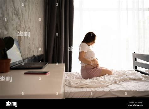 Attractive Pregnant Woman Sitting In Bed And Holding Her Belly Bedroom