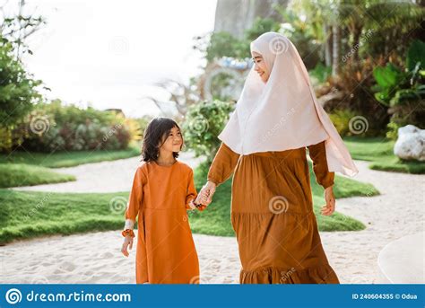 Madre Musulmana E Hija Caminando Y Cogiendo La Mano Imagen De Archivo