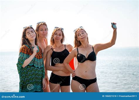 A Group Of Young Beautiful Women Take Selfies On The Beach In The