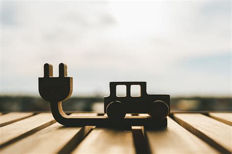 전선과 리튬 배터리가 있는 목조 자동차 연결된 충전 케이블이 있는 기술 배터리 고출력 전기 에너지 깨끗한 전기로 전기 자동차 및 모바일 장치에 배터리 개념에 대한 스톡 사진