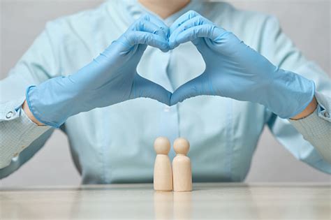 드레싱 가운과 장갑을 낀 소녀 의사는 추상적인 남성과 여성 위에 손으로 심장을 묘사합니다 갈색 머리에 대한 스톡 사진 및 기타