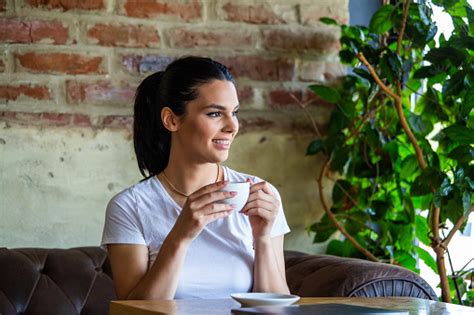 커피 한 잔과 아름 다운 젊은 여자입니다 여자는 아침에 일출과 함께 신선한 커피를 즐긴다 커피 가게 아름다운 여자는 창가에 앉아