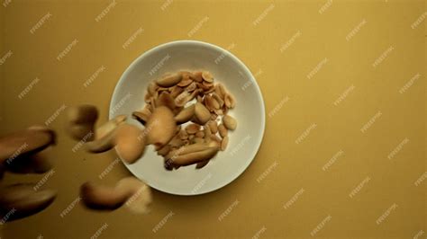 Premium Photo Top View Of Peanut Falling In To White Bowl With Yellow
