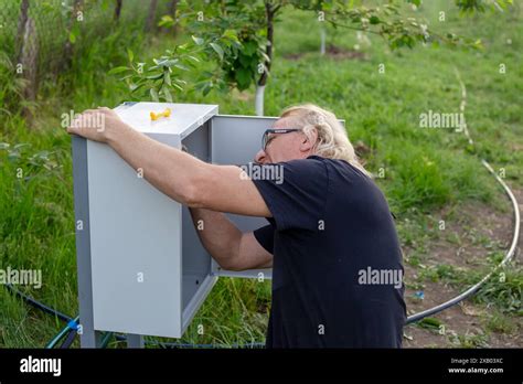 Assembling An Automatic Water Supply System For Drip Irrigation A Man Installs An Assembly Box