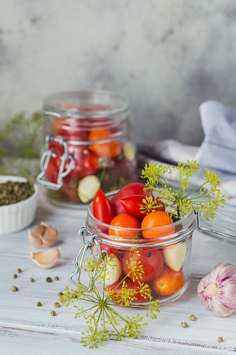 흰색 나무 테이블에 신선하고 절인 토마토 조미료 마늘을 보존합니다 건강한 발효 식품 가정용 통조림 채소 건강한 식생활에 대한