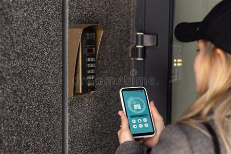 woman locking smartlock on the entrance door using a smart phone