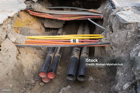 빨간색 골판지 파이프의 네트워크 케이블은 거리의 지하에 묻혀 있습니다 지하 전기 케이블 인프라 설치 통신 케이블이 많은 건설 현장 연료 및 전력 생산에 대한 스톡 사진 및