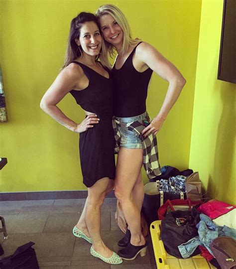 Two Women Standing Next To Each Other In Front Of A Yellow Wall And Suitcases