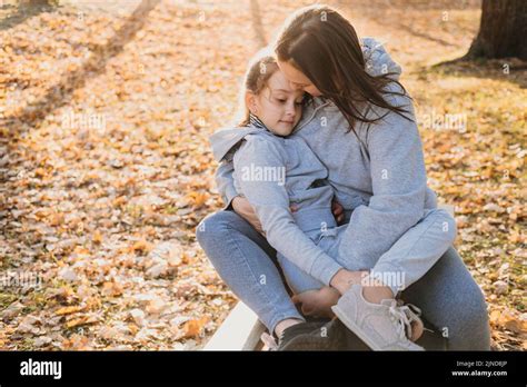 Mutter und Tochter verbringen gemeinsam Zeit im Herbstpark und sitzen auf einer Bank Glückliche