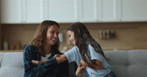 Cheerful Excited Young Mom Tickling Daughter Girl On Home Couch Stock