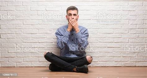 흰색 벽돌 벽 충격된 실수에 대 한 손으로 입을 덮고 앉아 젊은 성인 남자 비밀 개념입니다 가리기에 대한 스톡 사진 및 기타 이미지 Istock