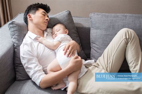 Young Chinese father and baby boy sleeping on sofa-High-res stock photo for download