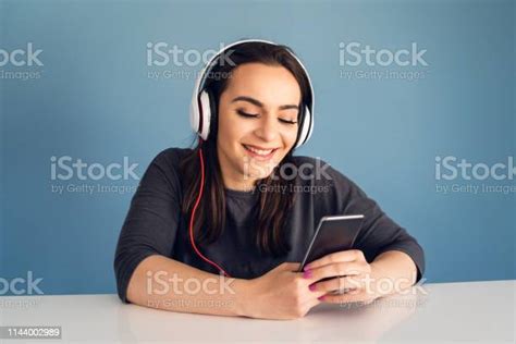 아름 다운 젊은 여자의 초상화는 웃 고 재미 있는 파란 벽 앞에 휴대 전화를 사용 하 여 집에서 음악을 듣고 가정 생활에 대한 스톡 사진 및 기타 이미지 Istock