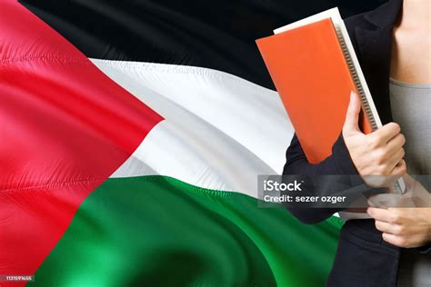팔레스타인 언어 개념 학습 백그라운드에서 팔레스타인 국기와 함께 서 있는 젊은 여자 책을 들고 교사 오렌지 빈 책 표지 팔레스타인 문화에 대한 스톡 사진 및 기타 이미지