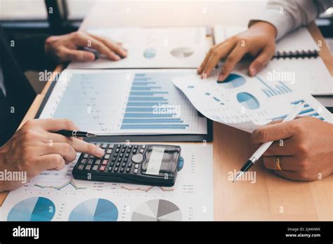 Two Business People Analyzing Summary Graph Reports Of Business Operating Expenses And Using