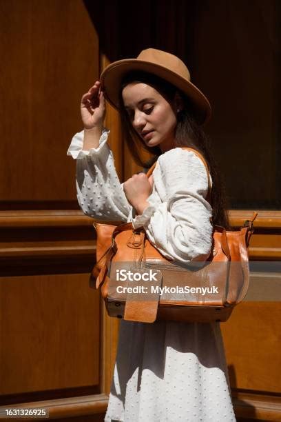 흰색 낭만적인 여름 드레스와 베이지색 모자를 쓰고 고급 가죽 가방을 들고 포즈를 취하는 갈색 머리 가방에 대한 스톡 사진 및 기타 이미지 Istock