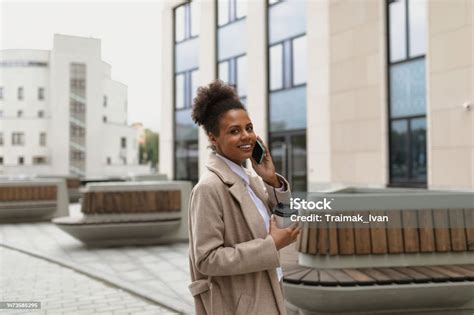아프리카 계 미국인 젊은 여자는 그녀의 얼굴에 미소를 지으며 비즈니스 센터 옆에서 휴대 전화로 이야기하고있다 25 29세에 대한 스톡 사진 및 기타 이미지 Istock