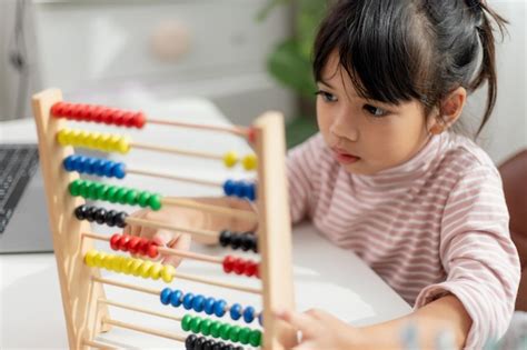 Premium Photo A Young Cute Asian Girl Is Using The Abacus With Colored Beads To Learn How To