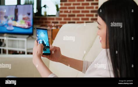 Playful Asian Woman Playing Space Shooter Game On Smartphone Device