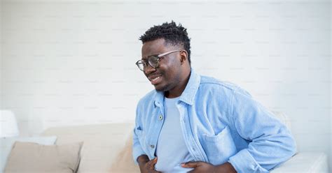 고통에 배를 잡고 있는 젊은 아프리카 남자 고통스러운 표정으로 배를 잡고 있는 역류 질환 남자 사진 Unsplash의 변비 이미지