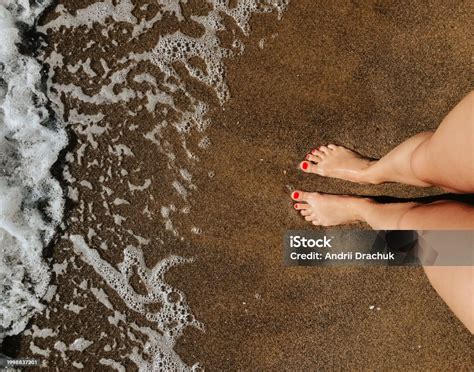 Woman Legs Barefoot At Sea Foam Waves On Sand Beach Summer Day Top View