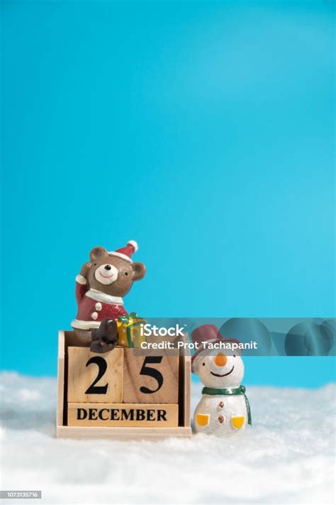 크리스마스 모자와 흰색 모직에 파란색 배경이 크리스마스 날짜 12 월 25 일에 나무 블록 달력에 눈사람을 입고 브라운 곰 텍스트 또는 콘텐츠를 위한 공간을 복사 합니다