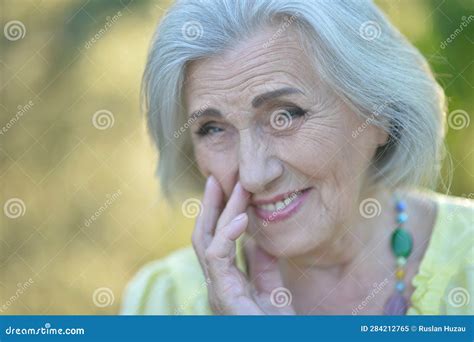 Close Up Portrait Of Happy Older Woman Standing Outside In Summer Stock