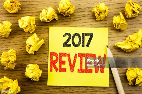 단어 2017 리뷰 쓰기입니다 나무 배경 스티커 메모 용지에 작성 하는 연례 요약 보고서에 대 한 비즈니스 개념 배경에 노란색 종이 접어 2018년에 대한 스톡 사진 및