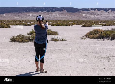 Woman In Blue T Shirt Black Leggings And White Baseball Cap Aiming At Self Resetting Target