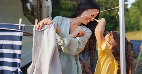 캠프장 캐러밴 가족 휴가 여행에서 야외에서 차로 옷을 매달고 있는 딸을 둔 어머니 사진 Unsplash의 의류 이미지