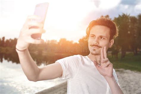Portrait Of Young Handsome Stylish Smiling Guy Makes Selfie Against The