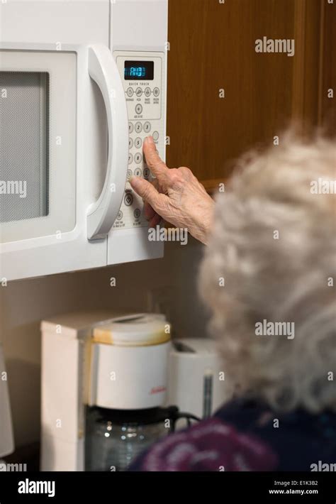 An Elderly Woman Operates A Microwave Oven A Senior Woman Operates A