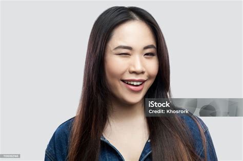 재미 있는 아름 다운 갈색 머리 아시아 젊은 여자의 이빨 미소 윙크 하 고 카메라를 보고와 서 화장과 캐주얼 블루 데님 재킷에 초상화 갈색 머리에 대한 스톡 사진 및 기타