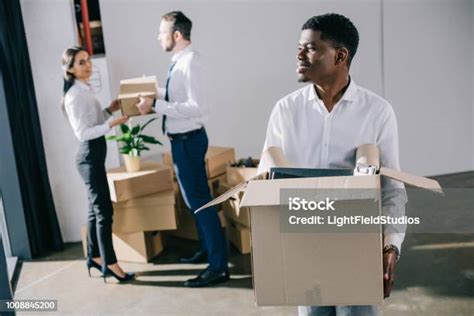 새로운 사무실에서 동료 들과 함께 이전 하는 동안 골 판지 상자를 들고 웃는 아프리카계 미국인 실업가 경영자에 대한 스톡 사진 및 기타 이미지 Istock