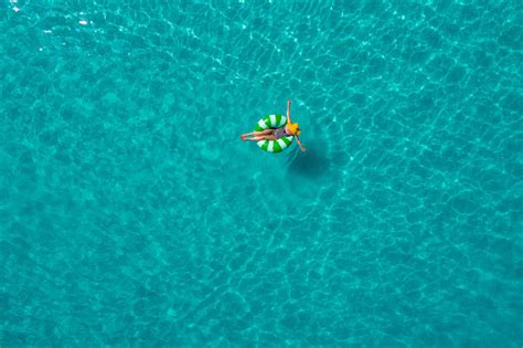 세이셸의 투명한 청록색 바다에서 수영 링 도넛에서 수영하는 슬림 한 여성의 공중 보기 소녀와 여름 바다 풍경 아름다운 파도 다채로운 물 드론에서 보기 공중 뷰에 대한 스톡