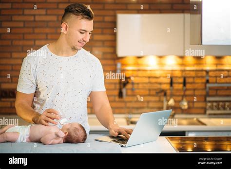Dad Trying To Work While Standing With His Newborn Babe In Home Office Interior Stock Photo Alamy