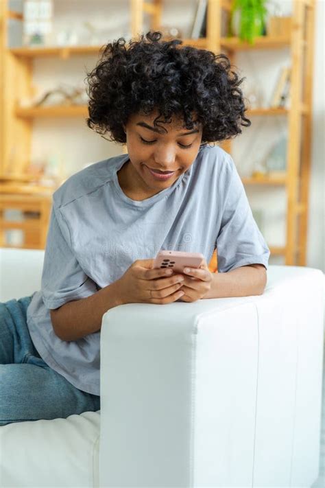 African Girl Holding Smartphone Touch Screen Typing Scroll Page At Home