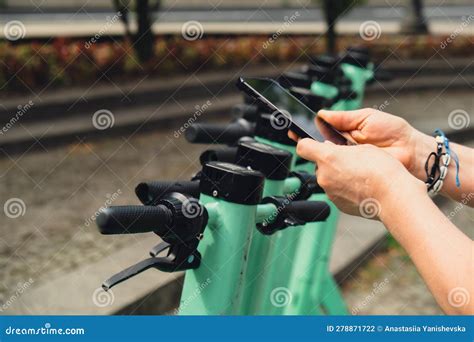 Female Hand Uses Mobile Phone To Scan QR Code On Electric Scooter On The Street On E Scooter