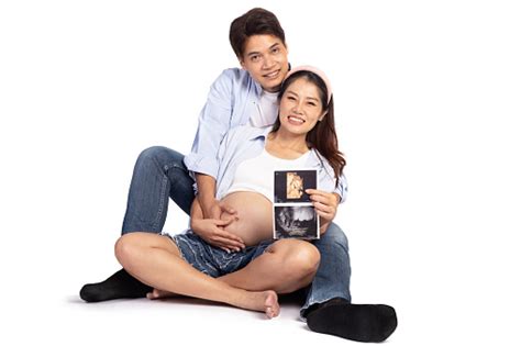 하얀 배경에 고립된 행복한 가족 아시아 커플 남편과 임신 아내가 함께 앉아 있습니다 큰 배를 가진 아름다운 임산부는 새 아빠와 함께 앉아 초음파 아기 아기 사진을 들고