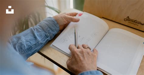 테이블에 앉아 책에 글을 쓰는 사람 사진 Unsplash의 무료 직장 이미지