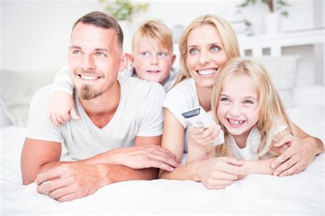 Familia Feliz Tumbada En La Cama Viendo La Tele Foto Premium