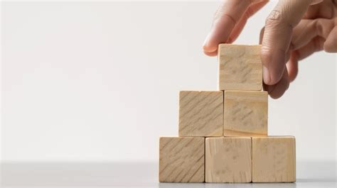 Premium Photo Hand Stacking Wooden Blocks To Build A Tower Representing Growth And Development