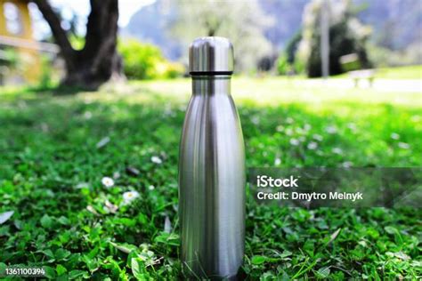 녹색 잔디에 재사용 강철 열병 복사 공간이있는 흐린 잔디의 배경에 은색의 강철 열수 병 플라스틱이 없습니다 폐기물이 없습니다 공간을 복사합니다 제로 폐기물 아니 플라스틱