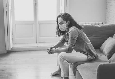 집에서 소파에 우울 보호 얼굴 마스크를 가진 슬픈 아픈 라틴어 여자 코로나바이러스 사망 잠금 및 사회적 불변속에서 피곤하고 걱정스러운 우울증을 느끼는 절망적 인 여성 정신