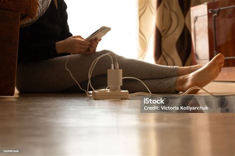 소녀는 아파트 바닥의 연장 코드로 전화를 충전하고 소켓에 충전하기 위해 전화를 넣습니다 Usb 케이블에 대한 스톡 사진 및 기타 이미지 Usb 케이블 네트워크 연결