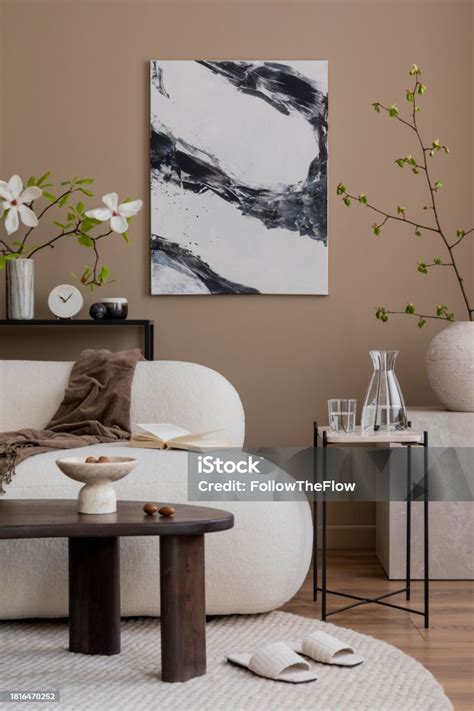 모형 포스터 프레임 부클 소파 나무 커피 테이블 원형 카펫 목련이 달린 꽃병 개인 액세서리가 있는 따뜻한 거실 인테리어의 미적