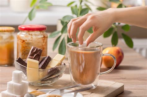 소년의 손은 우유와 차 또는 커피 한 잔 위에 설탕 큐브를 들고있다 다양한 종류의 과자와 설탕이 식탁에 놓여 있습니다 꿀에 대한 스톡 사진 및 기타 이미지 Istock