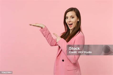 자 켓을 입고 흥분 된 젊은 여자의 초상화는 입을 열어 손으로 가리키는 검지 손가락 옆에 파스텔 핑크 배경에 고립 사람들은 진심으로 감정 라이프 스타일 개념입니다 복사